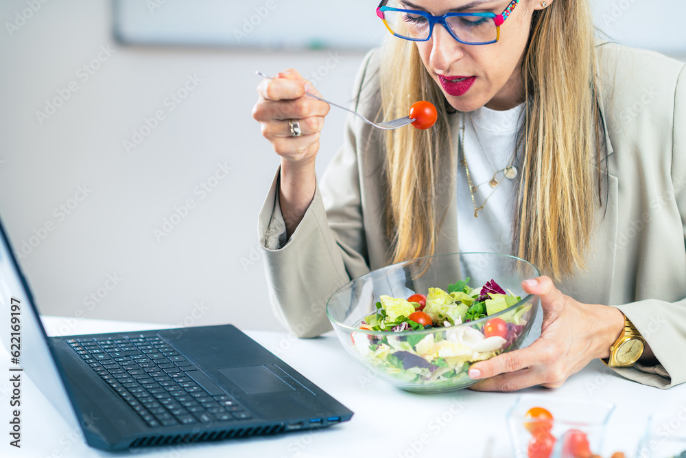 Healthy eating at work. Woman indulges in a delightful fresh salad at ...