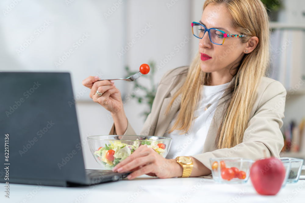 Foto de Healthy eating at work. Woman indulges in a delightful fresh ...