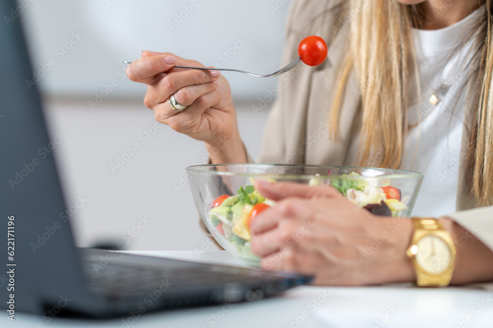 Healthy eating at work. Woman indulges in a delightful fresh salad at ...