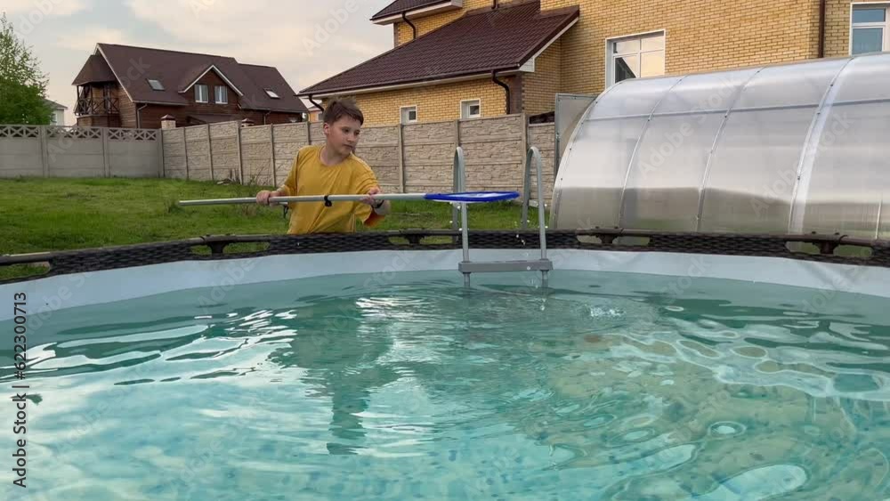 boy Cleaning a swimming pool with a metal frame with a net from dirt ...