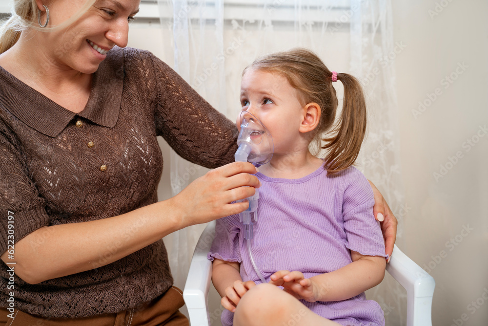 Cute little girl inhaling mist form nebulizer at home. Holding mask ...