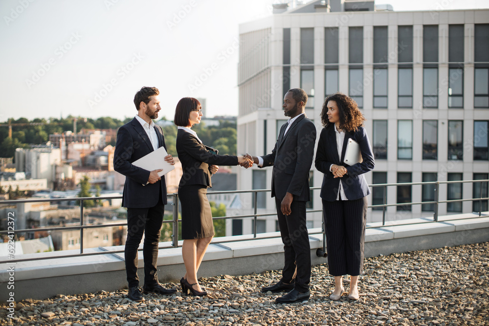 Biracial business partners shaking hands to confirm agreement of mutual ...