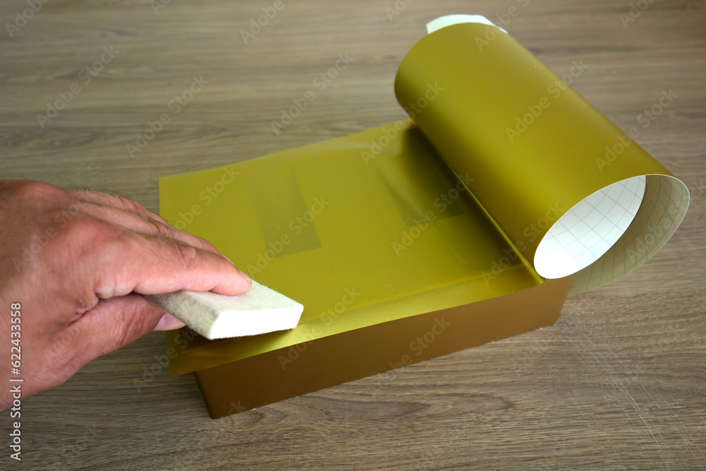 Rolling up a plastic letter of outdoor advertising with a gold-colored ...