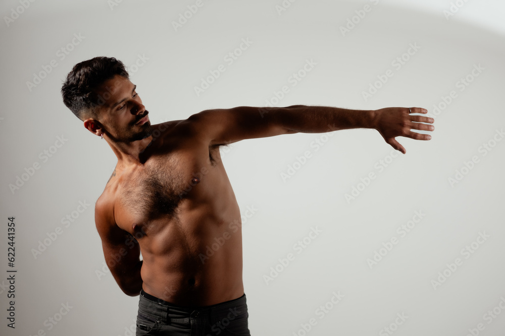 An athletic man looks at his outstretched hand, flexing his upper body ...