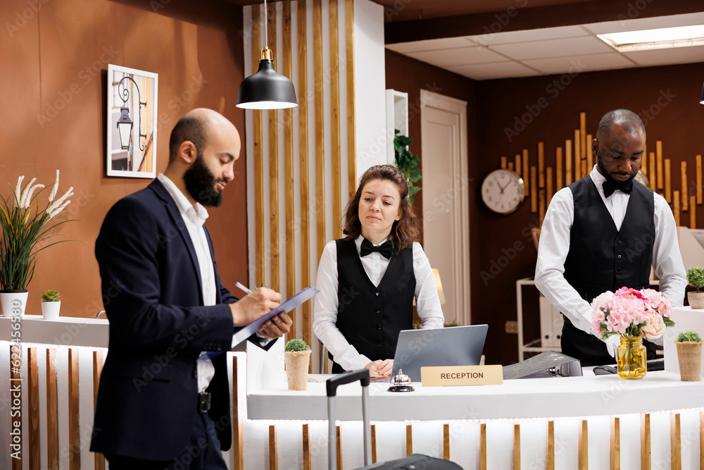 Entrepreneur arrive in hotel reception, signing forms to register and ...