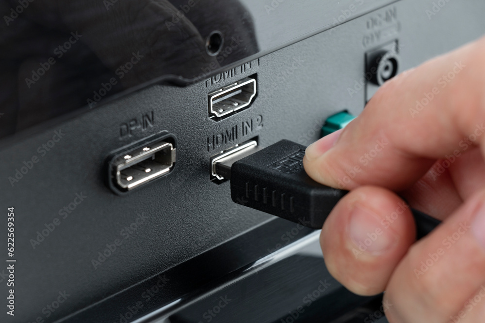 HDMI connector connected to the monitor, hand insert a HDMI cable Stock ...