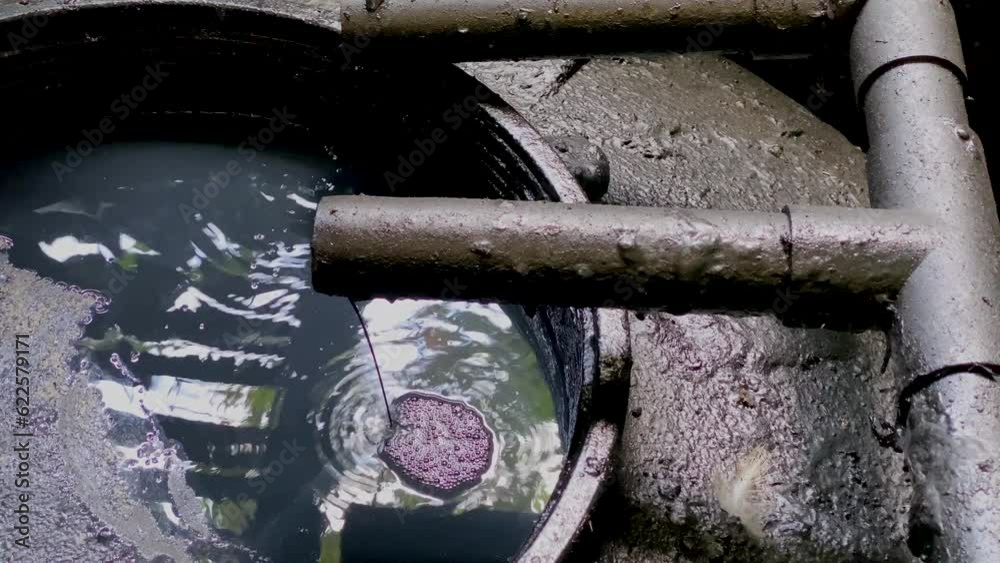 Black chemical wastewater coming out from pipe to storage tank from ...