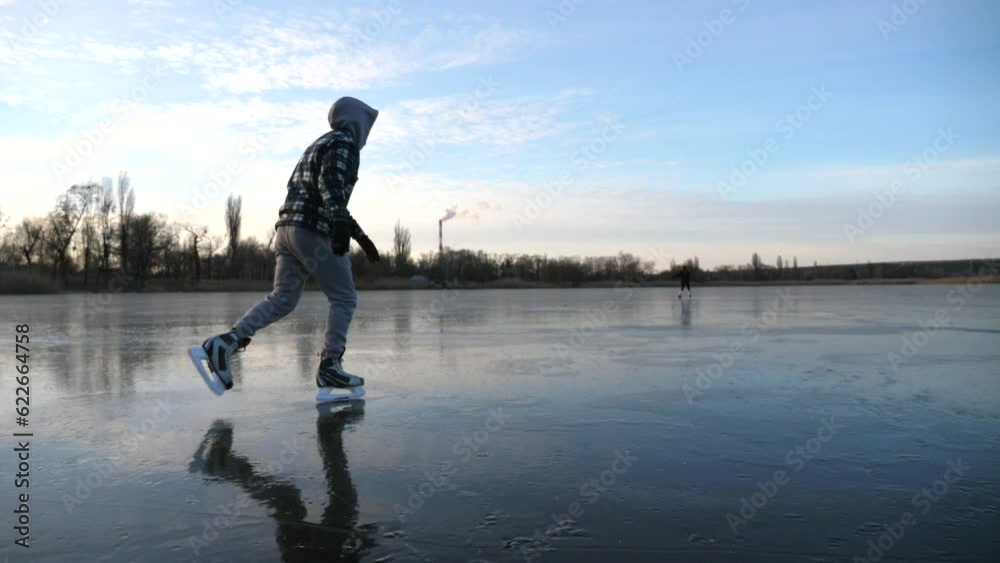 Following to young man shod in figure skates sliding on ice. Guy ...