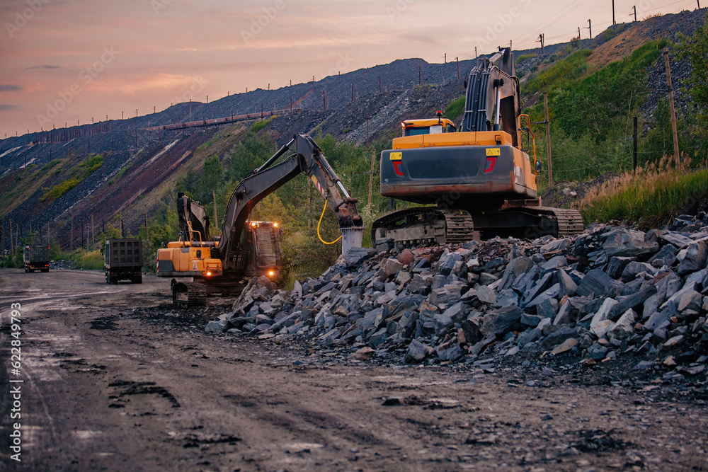 Excavators and dump trucks working on earthmoving at open pit mine in ...