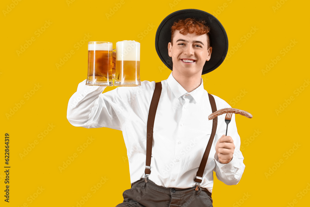 Young man in traditional German clothes with beer and sausage on yellow ...