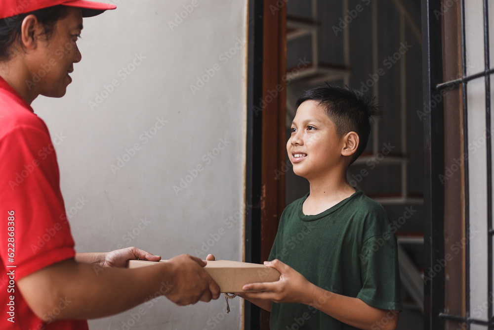 Little Asian kid receiving pizza box from delivery man at the door ...