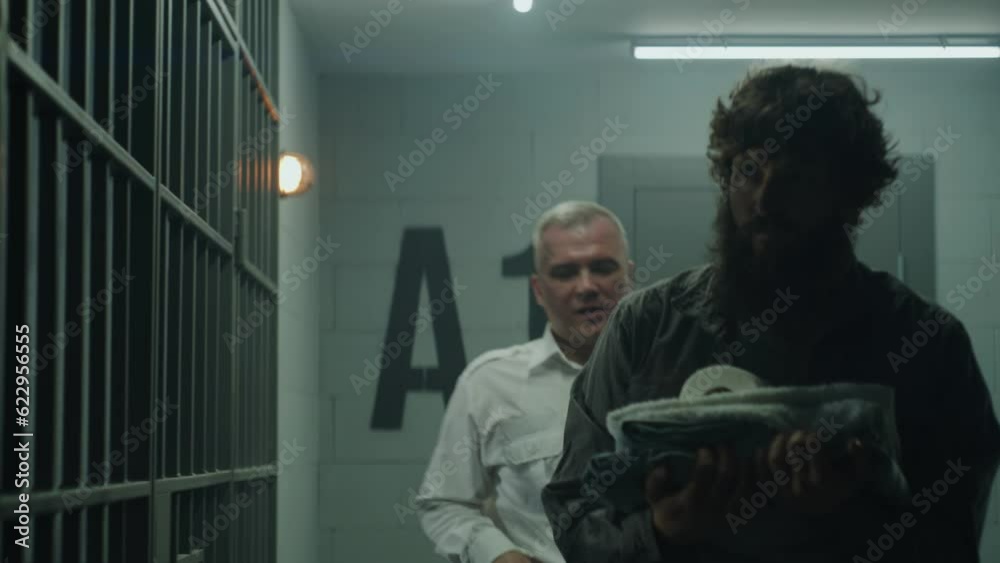 Jailer leads male criminal to prison cell, opens and locks it with keys ...