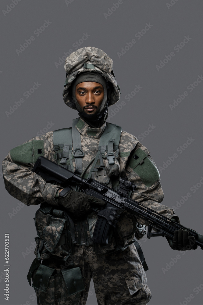 Dark skinned soldier in NATO uniform and helmet poses with a serious ...