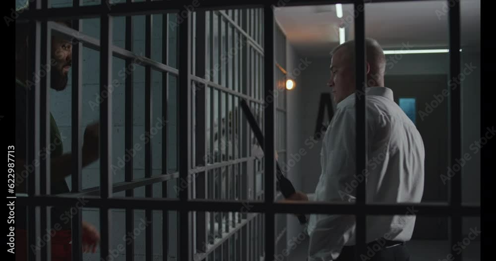 Angry prison officer watches criminals in prison cells, speaks with ...