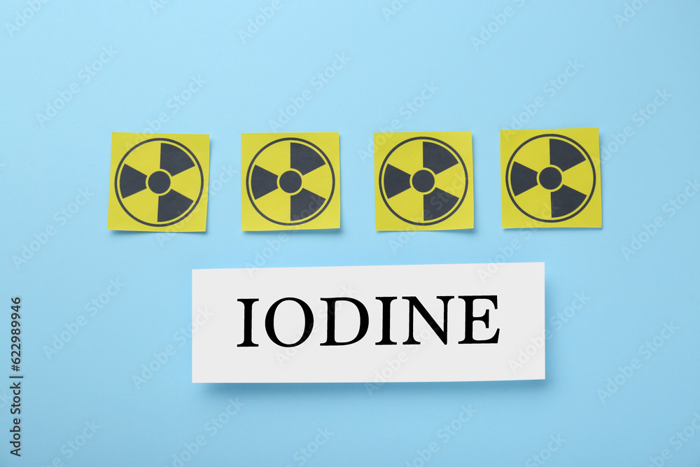 Paper note with word Iodine and radiation signs on light blue ...