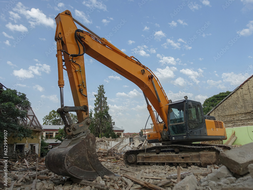 Heavy yellow excavator machine bagger clears the ground where the house ...