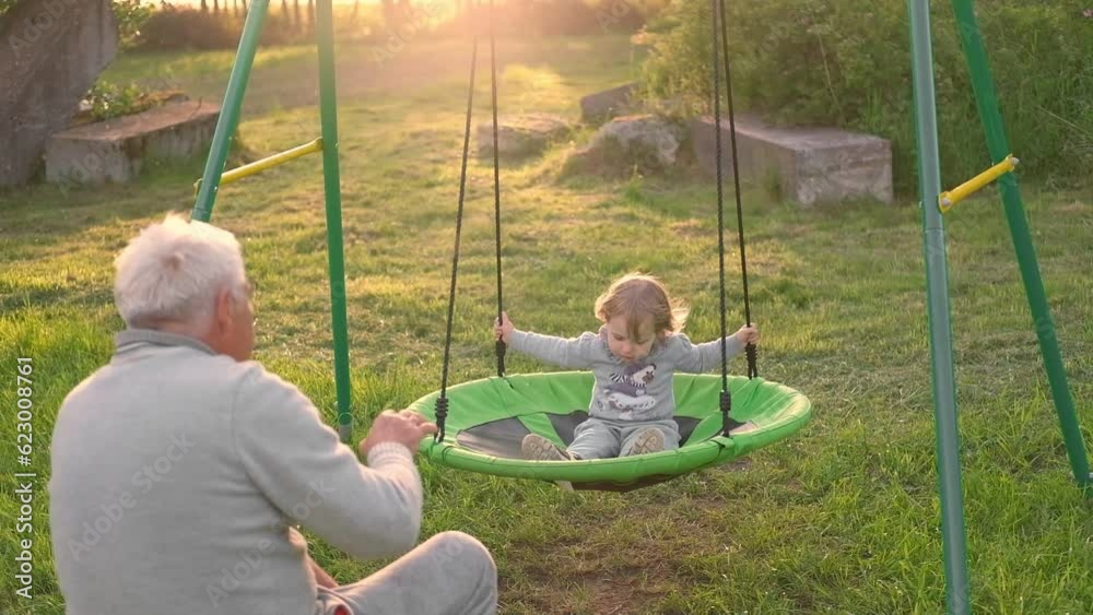 Grandfather swinging a child in summer at sunset. Grand dad and ...