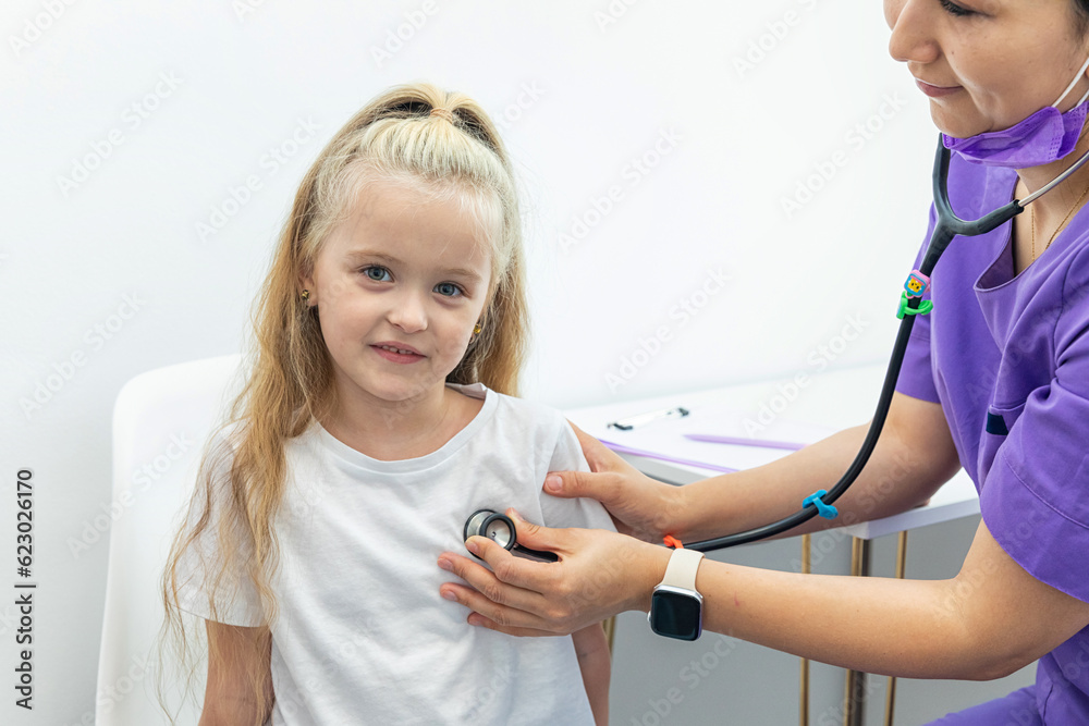 Child at medical checkup at hospital or clinic. Friendly female doctor ...
