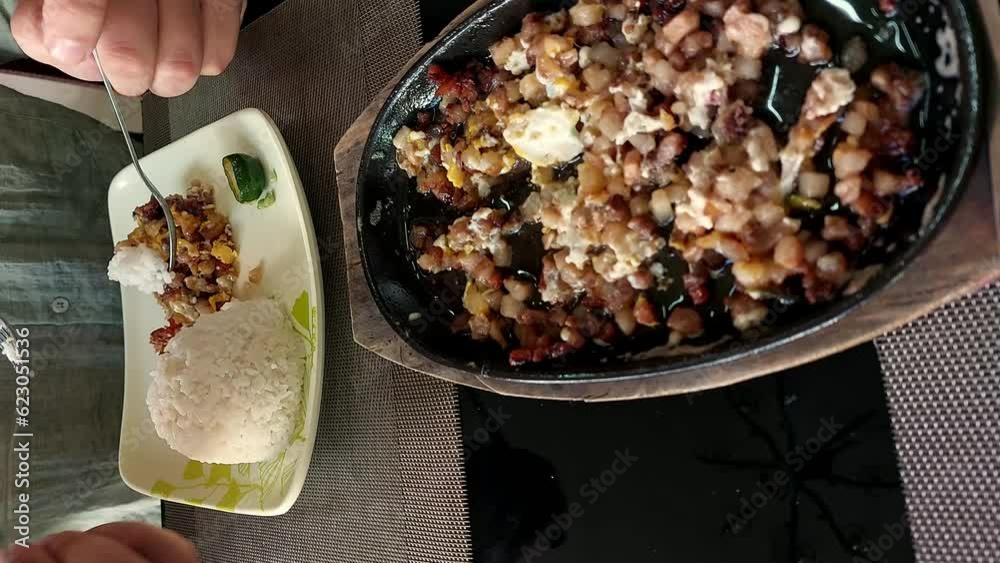 Candid moment of a tourist eating pork sisig with rice, an authentic ...