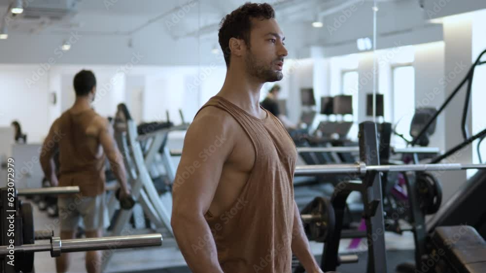 European man workout with dumbbells training shoulders in gym ...