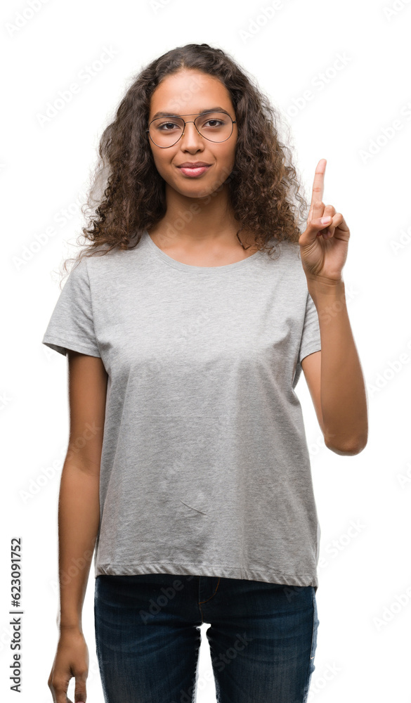 Beautiful young hispanic woman wearing glasses showing and pointing up ...