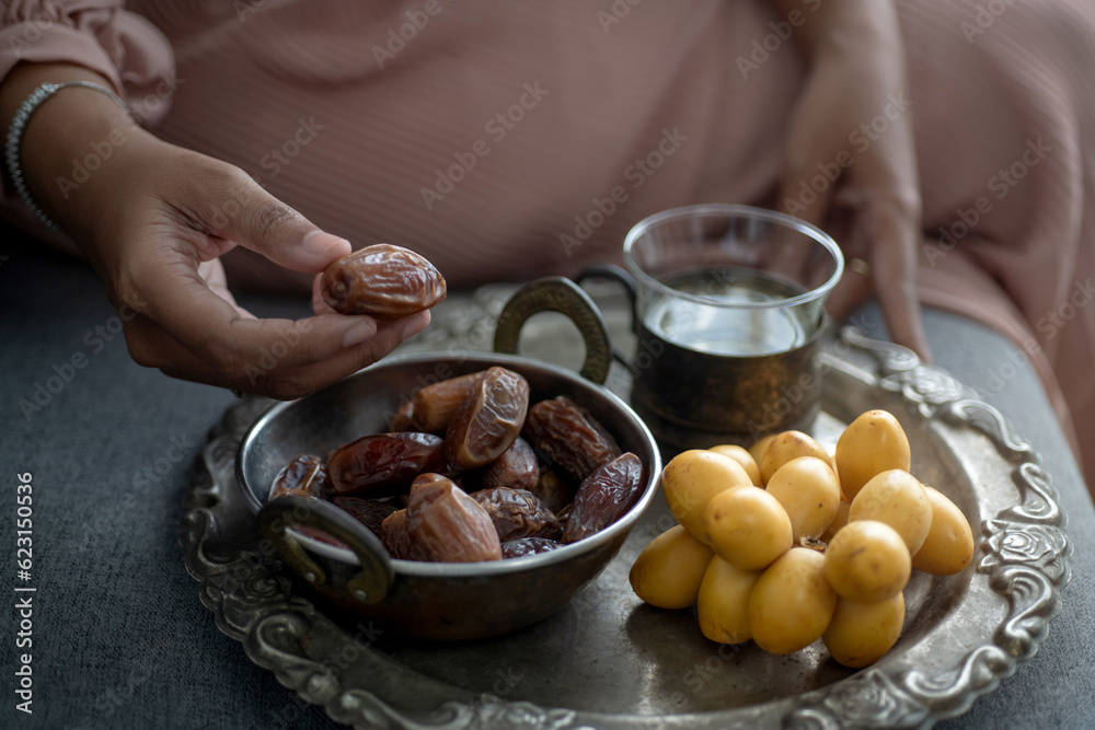 Muslim woman picking dried dates in metal bowl and fresh yellow date ...
