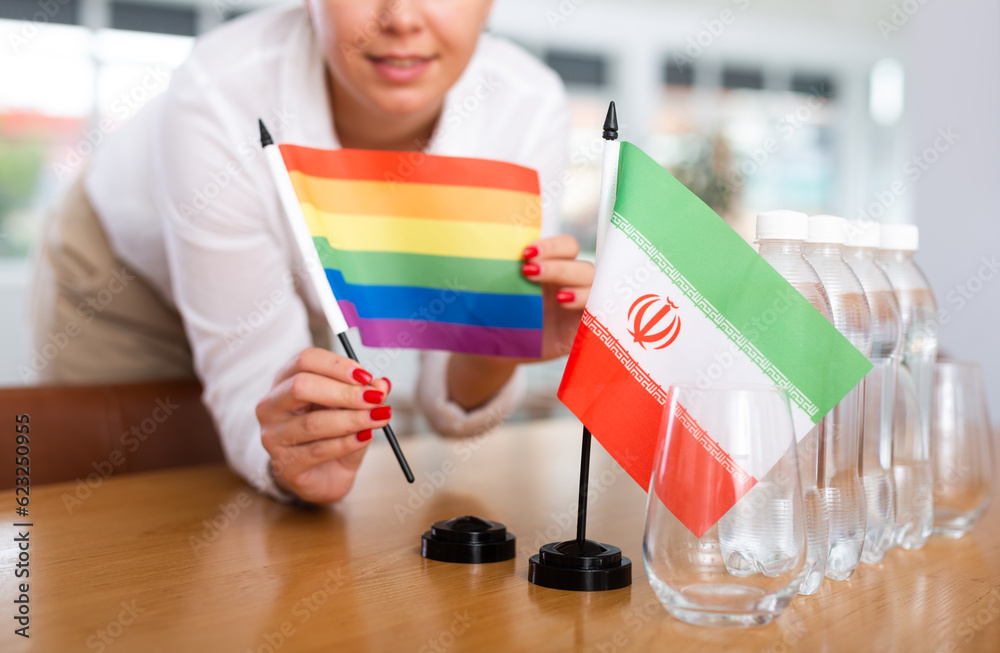 Little flag of Iran on table with bottles of water and LGBT flag put ...