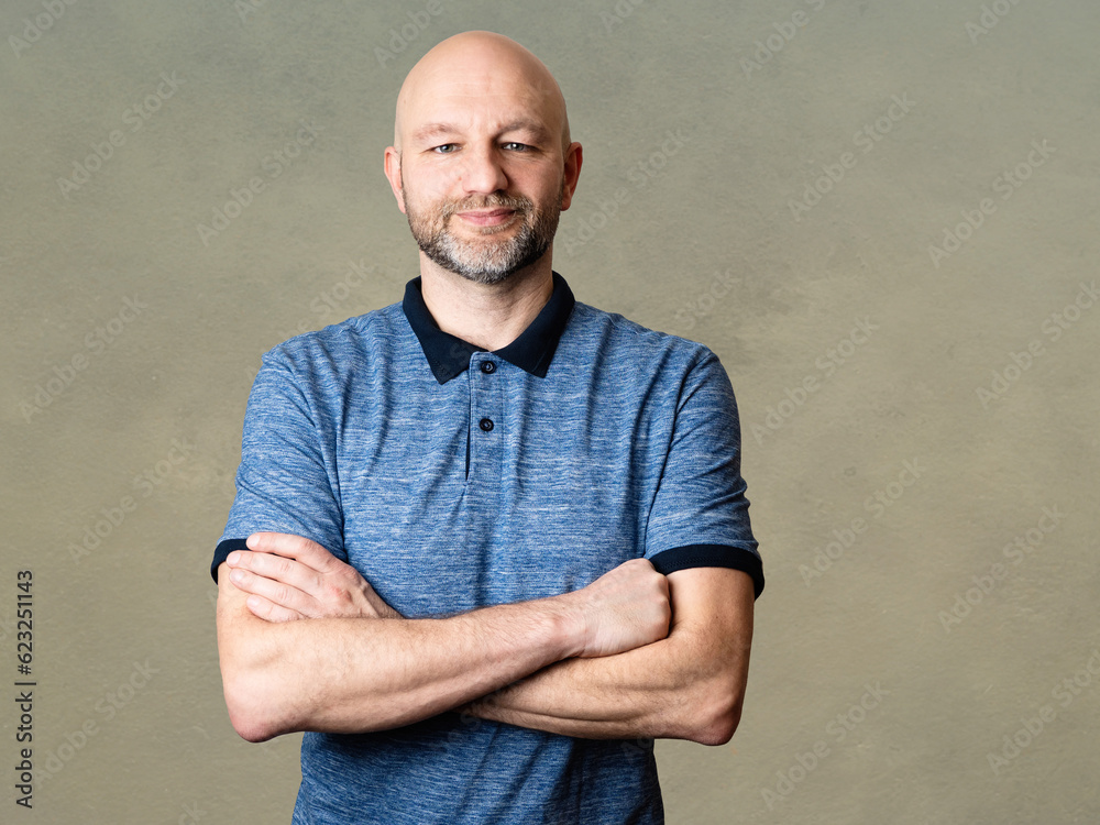 Portrait of a bald man in blue shirt on a light color background. The ...