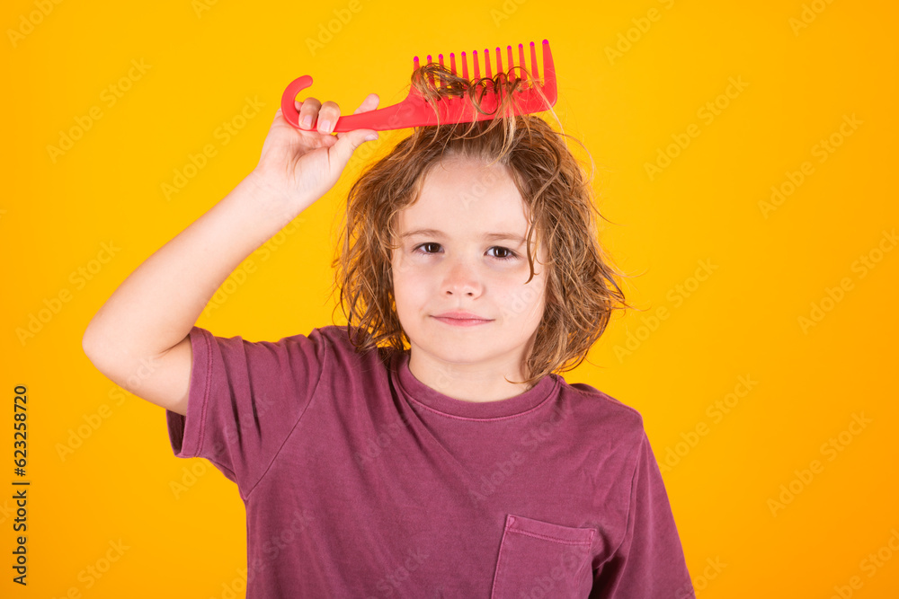 Cute child with curly blonde hair holding comb hairbrush for combing ...