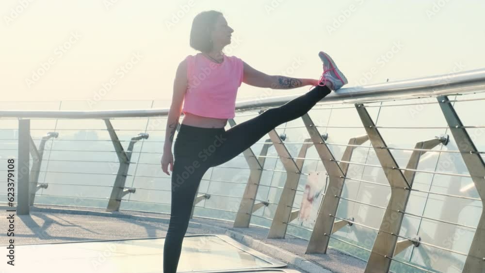 Woman keeps hands on railing with leg outstretched. Lady in pink top ...