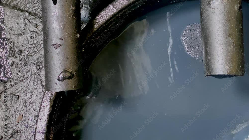 Black chemical wastewater coming out from pipe to storage tank from ...