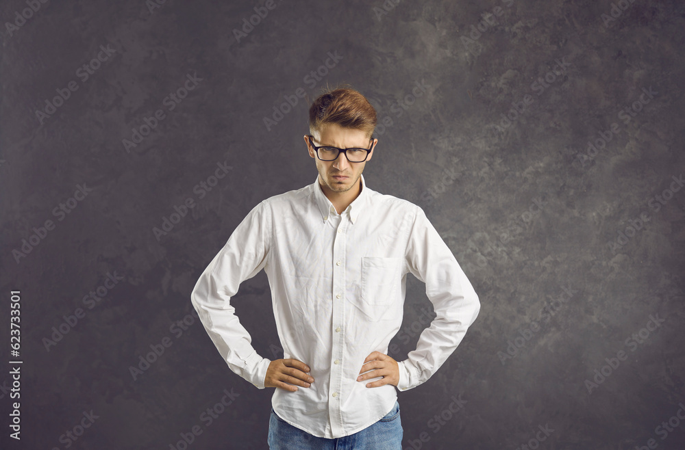 Portrait of offended and angry young man standing with frown on gray ...
