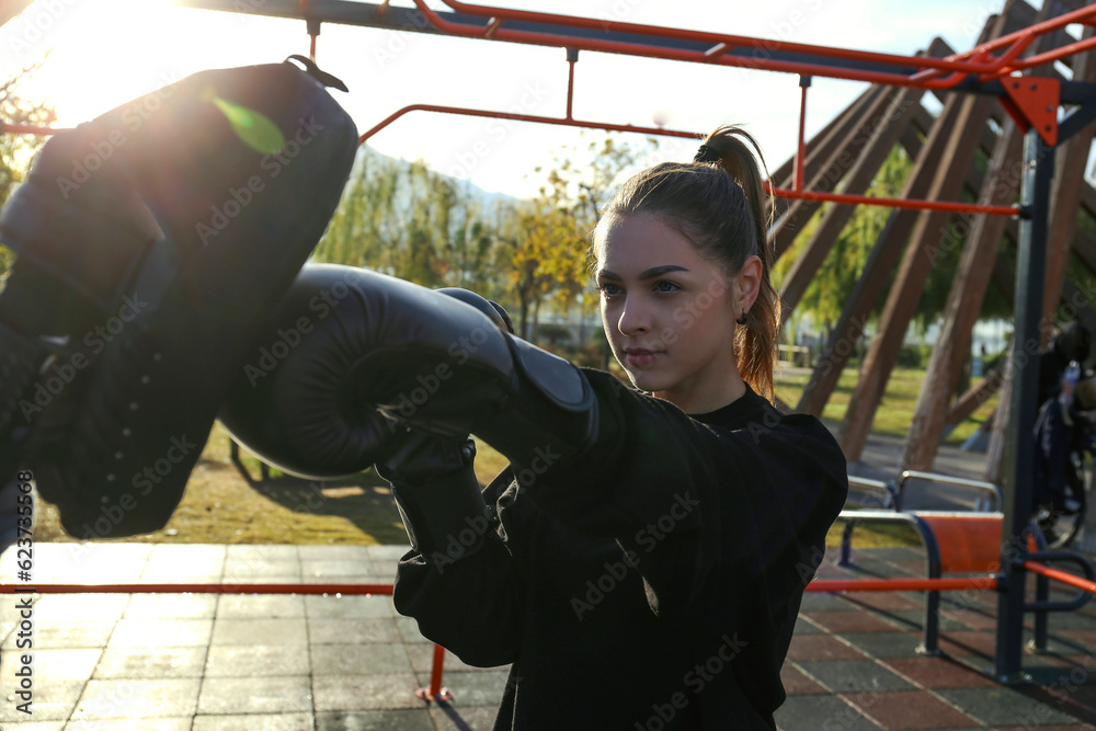Young woman training with her personal striking coach and hitting pads ...