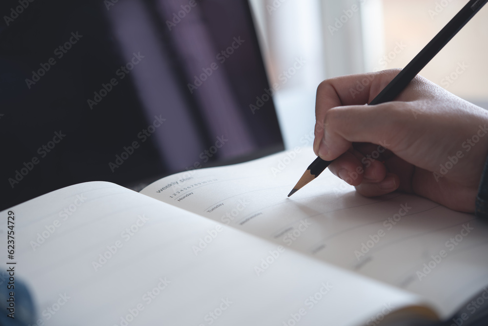 Close up of woman hand with a pencil writing, planning schedule ...