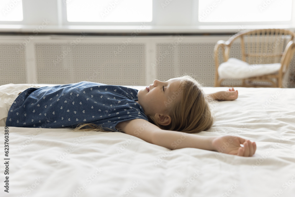 Positive peaceful relaxed little girl kid resting on bed with white ...