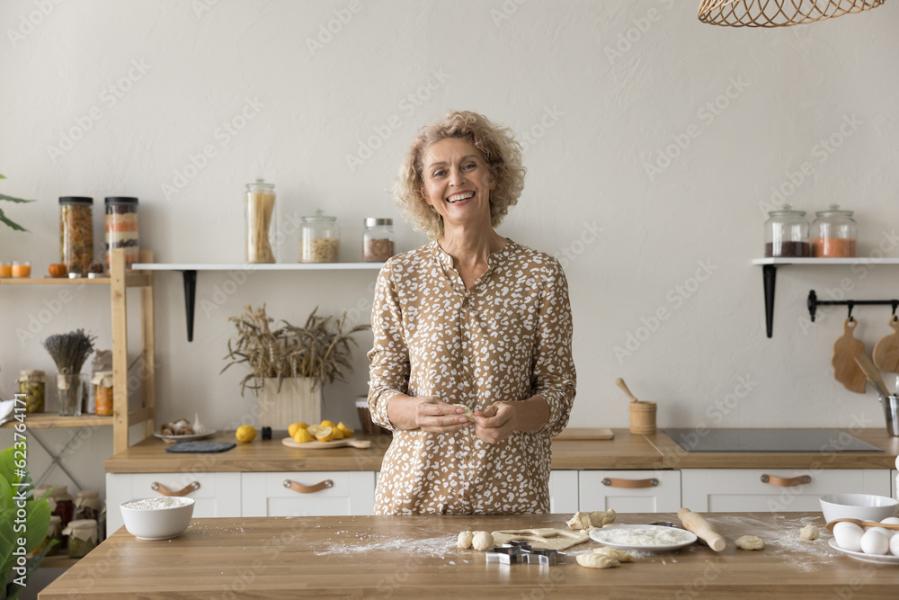 Happy pretty mature lady baking homemade cookies in kitchen, holding ...