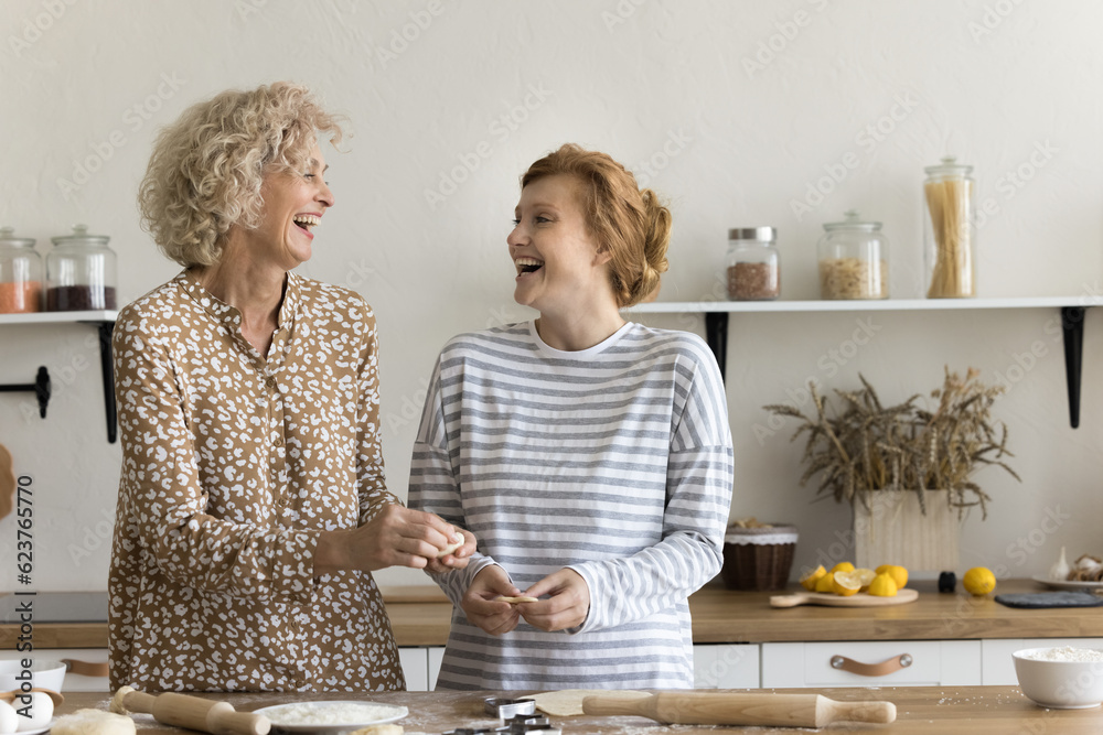 Joyful excited mom and adult daughter baking sweet homemade pastry ...
