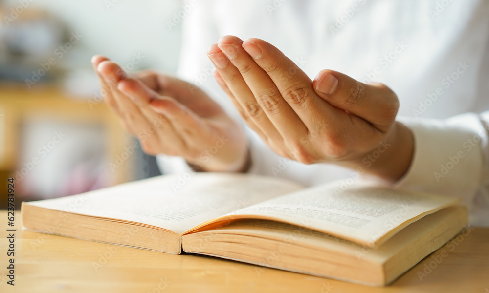 close up young man hand gesture to pray while reading holy book in home ...