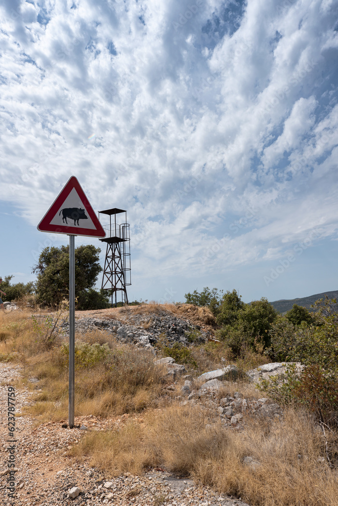 Road sign with attention to wild boar with an observation tower behind ...