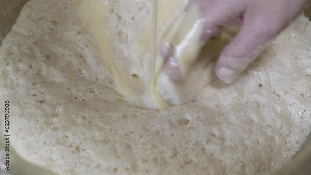 Female Hand Stirring Foamy Yeast Dough in Bowl with Addition of Melted ...