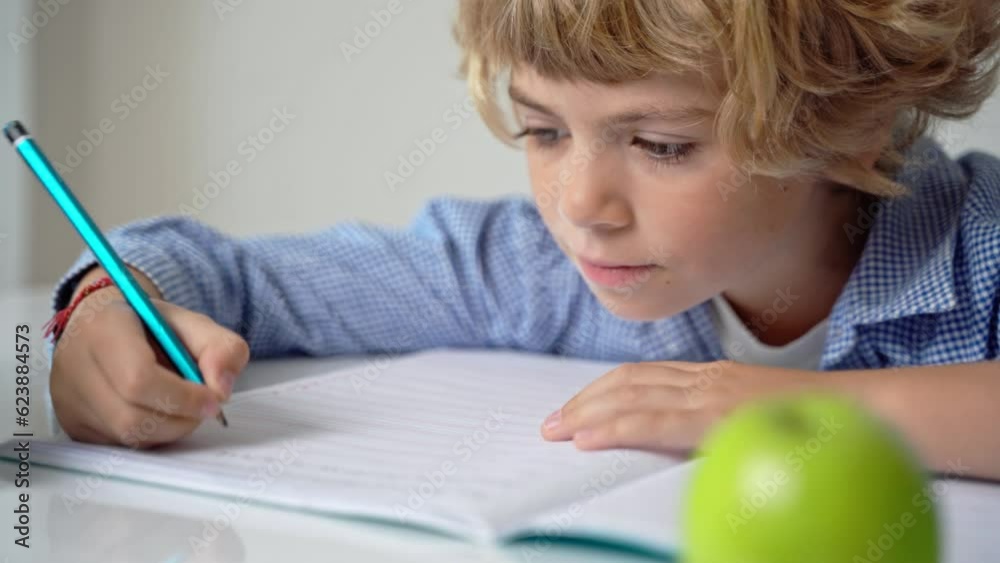 Elementary school student boy or girl writing letters, studying at desk ...