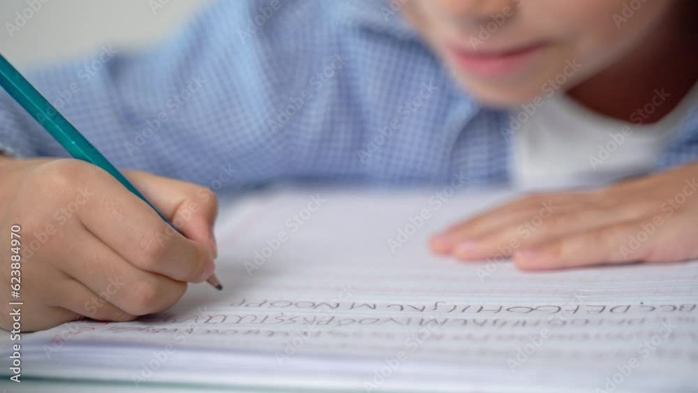 Elementary school student boy or girl writing letters, studying at desk ...