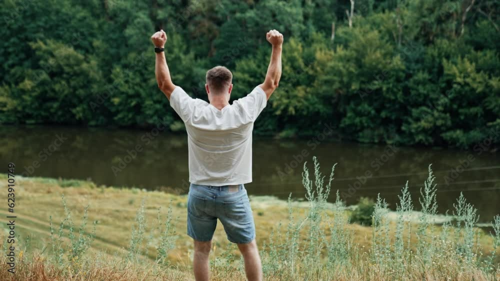 Rear view of a strong muscular man in white t-shirt and jeans shorts ...