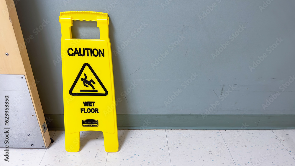 Bright yellow caution sign with 'wet floor' text symbolizes potential ...