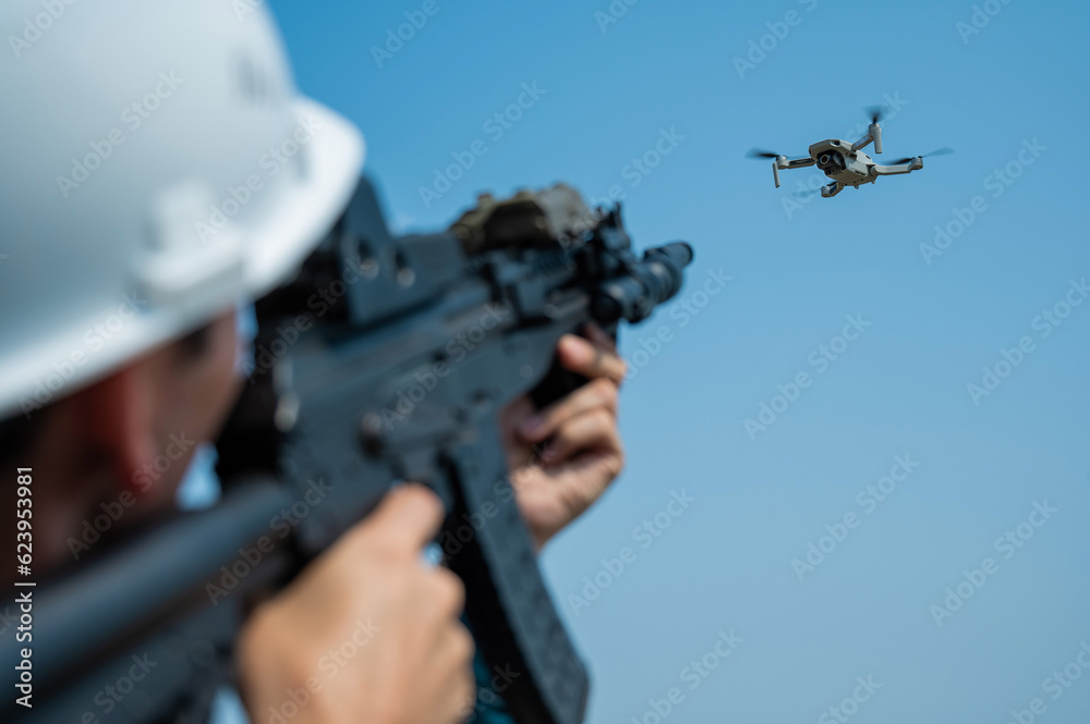 Caucasian man in a helmet shoots a flying drone with a rifle. Stock ...