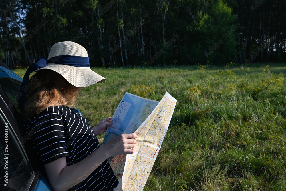 Rear view shot of couple driving on country road. Woman holding map and ...