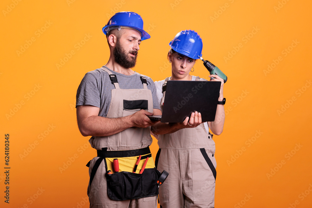 Professional builders in studio holding laptop, looking at building ...