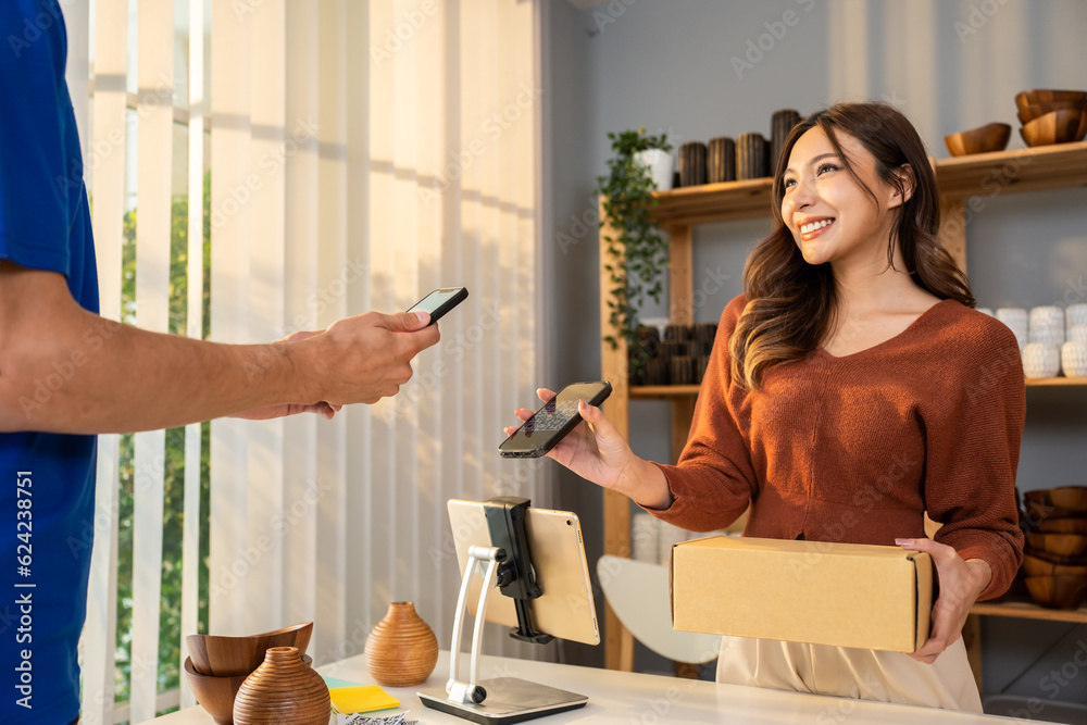 Attractive male customer using mobile phone paying for goods package ...