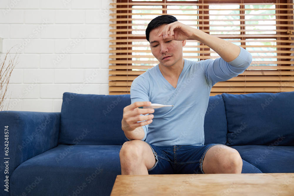 young man have a high fever from checking a digital thermometer measure ...