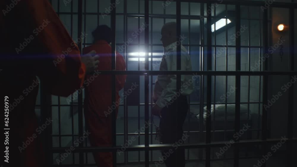Jailer locks male criminal in prison cell. Inmate in orange uniform ...
